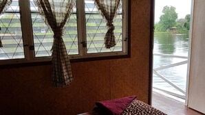 Quarto com uma cama, janela com cortinas e vista para um corpo de água lá fora.