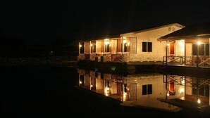 Um edifício de vários andares com janelas iluminadas e reflexo na água.