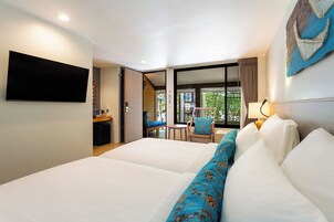 Quarto de hotel com cama, escrivaninha, cadeira e televisão.