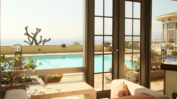 Quarto com vista para uma piscina e varanda com mobiliário de exterior.