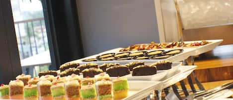 Mesa de buffet com diversos doces e vista pela janela.