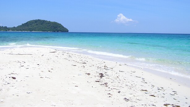 Uma praia com areia branca e águas turquesa cristalinas.