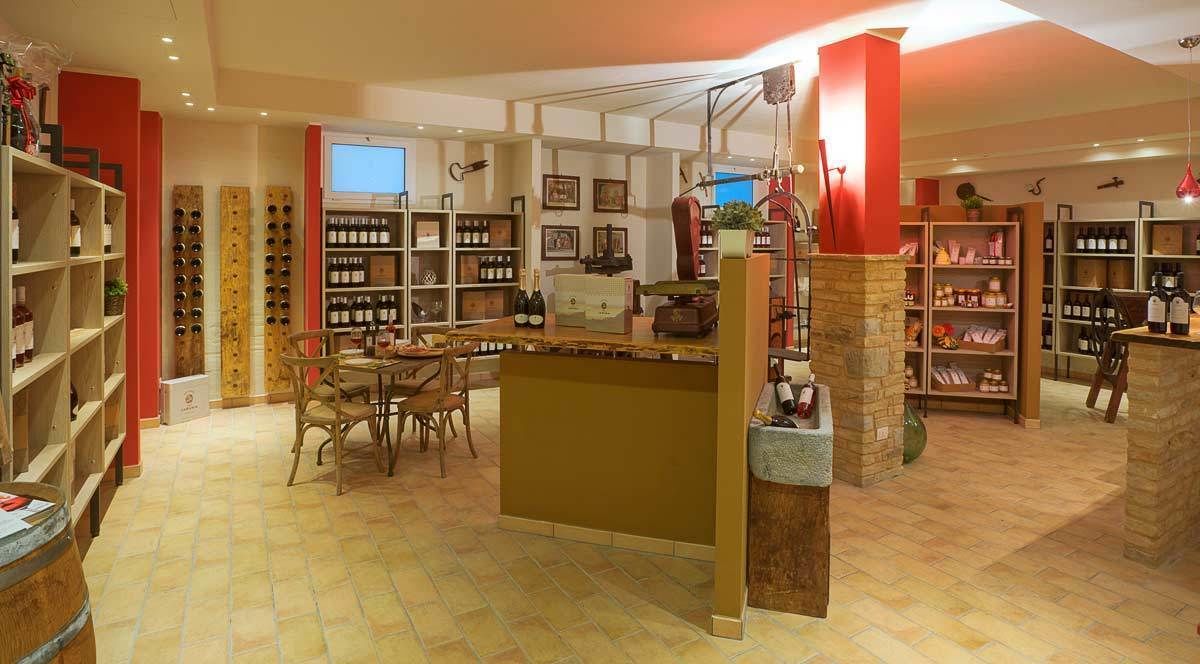 Uma loja de vinhos com prateleiras cheias de garrafas, um balcão e uma área de estar.