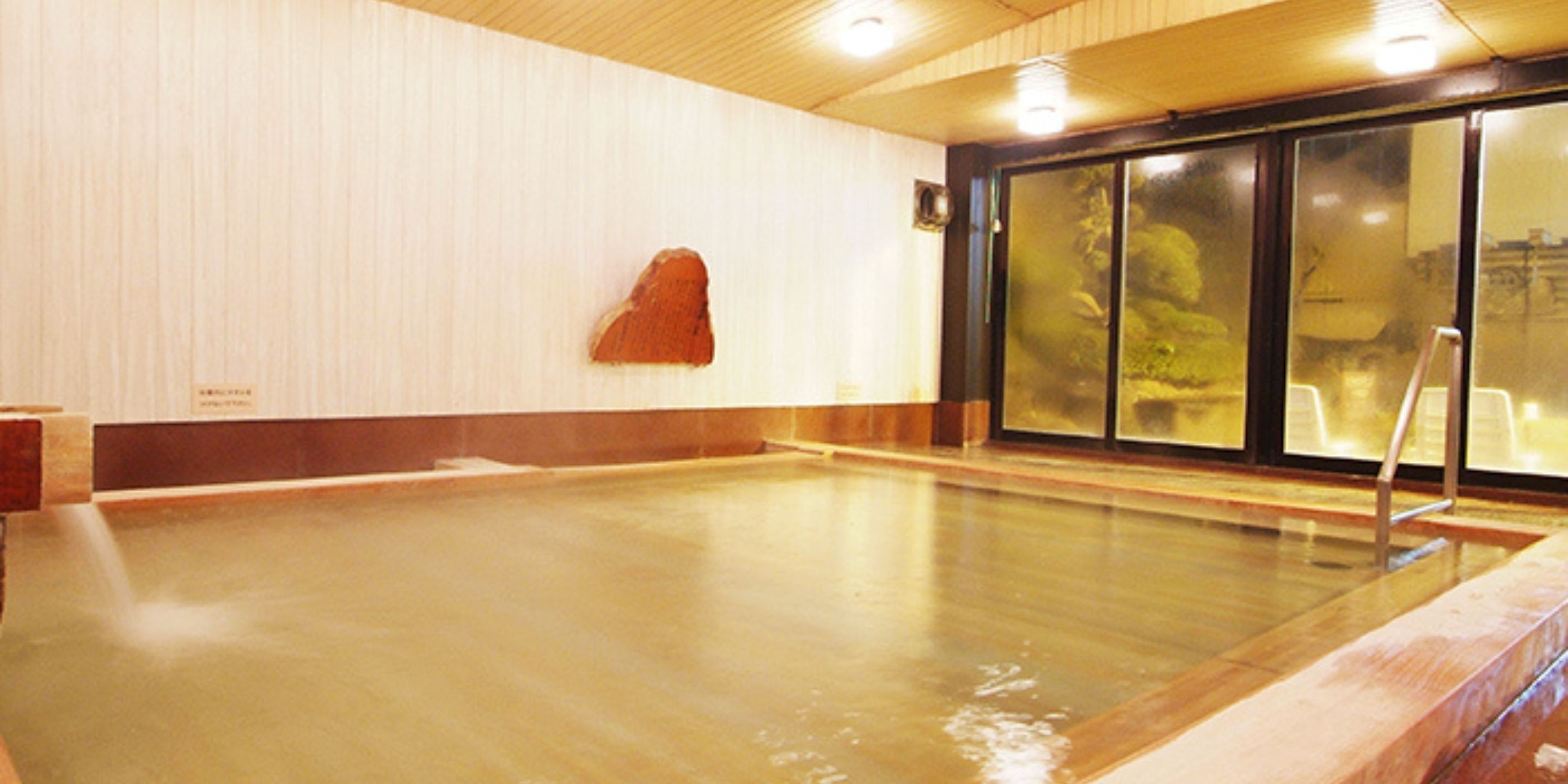 Piscina com piso de madeira e parede de vidro.