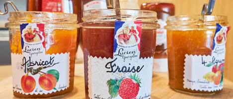 Três potes de compota de fruta Lucien Georgeselin sobre uma superfície de madeira.