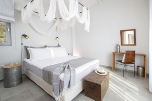 Quarto com cama, mesa de cabeceira, abajur, cadeira e uma pequena caixa de madeira.