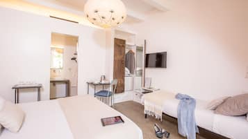 Quarto de hotel moderno com cama, escrivaninha, cadeira, televisão e banheiro.