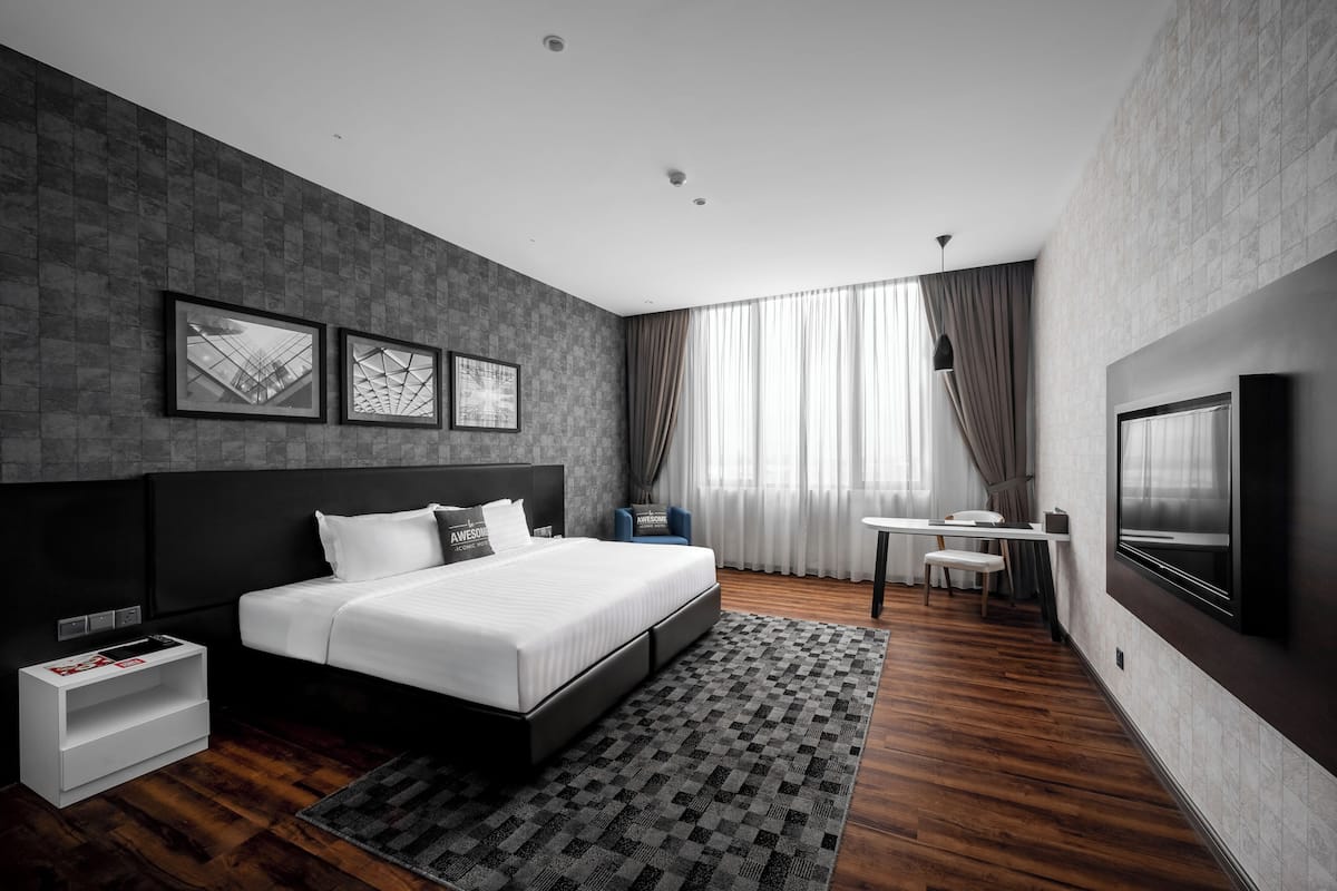 Quarto de hotel moderno com uma cama grande, uma escrivaninha e uma televisão.