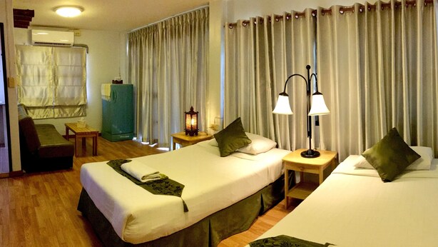 Quarto de hotel com duas camas, uma escrivaninha, uma cadeira, um abajur e um aquecedor.