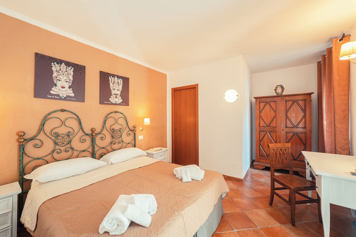 Quarto de hotel com cama, escrivaninha e armário.