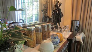 Um buffet de café da manhã com diversos alimentos, um espelho decorativo e uma estátua.