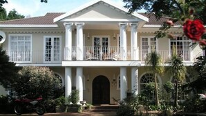 Uma casa de dois andares com varanda da frente, colunas e sacada.