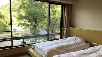 Quarto com uma janela grande, uma cama e um banquinho.