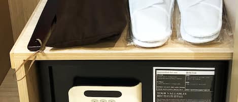 Um armário de madeira com um telefone preto e branco, uma bolsa marrom e um par de chinelos brancos.