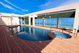 Convés de navio de cruzeiro com piscina, escorregador e vista para o oceano.