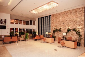 Um lobby moderno com balcão de recepção, área de estar e uma janela grande.