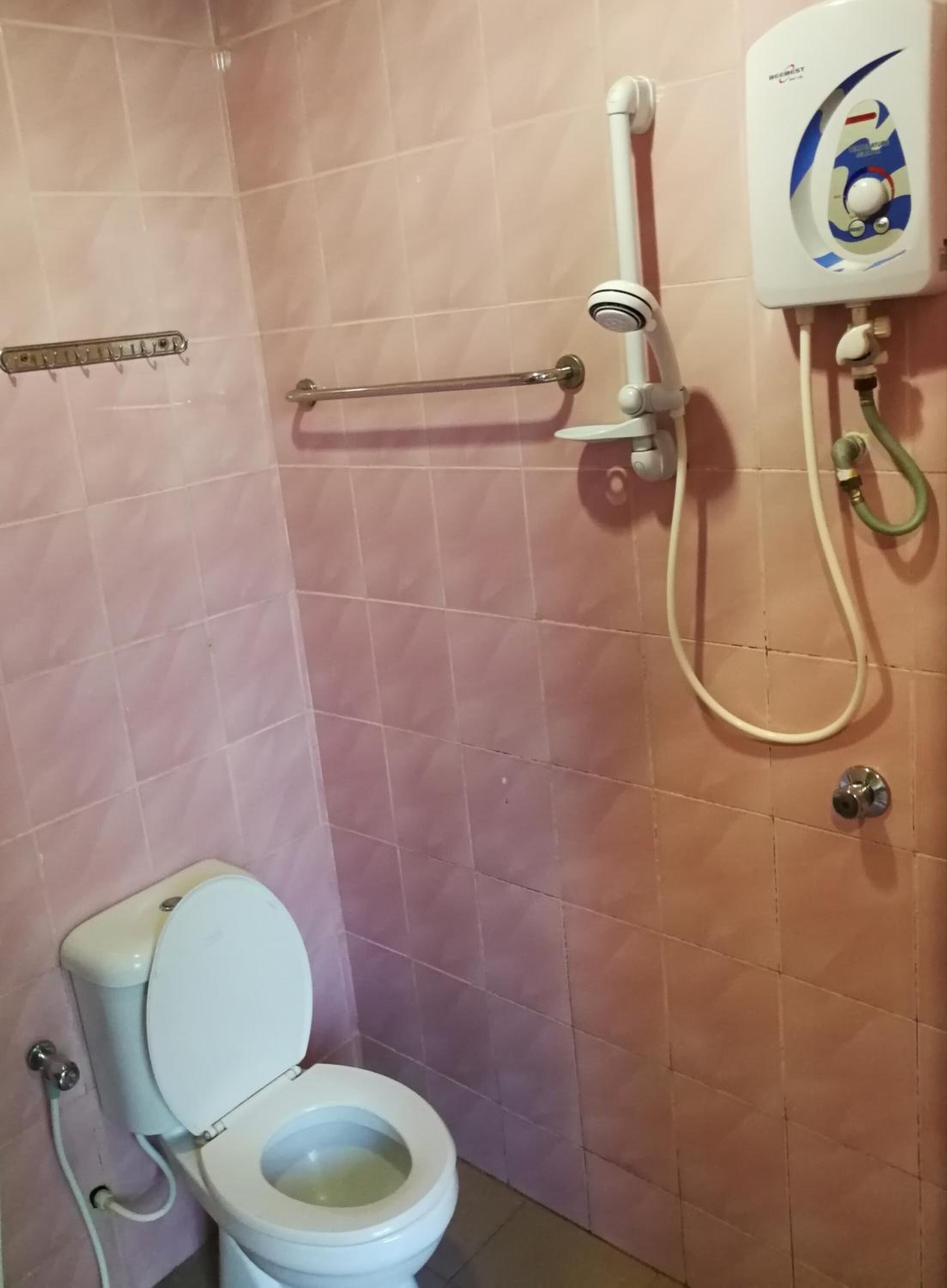 Uma casa de banho pequena com sanita, barras de apoio e chuveiro.