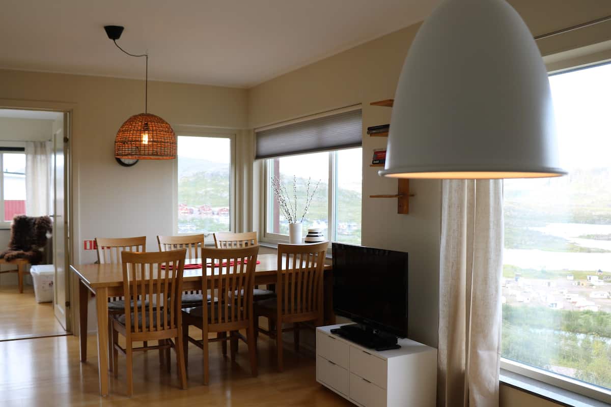 Uma sala de jantar com mesa, cadeiras e televisão.