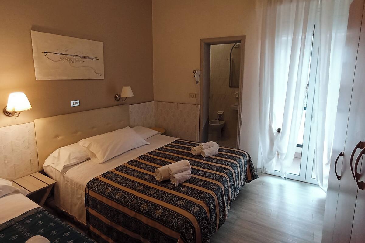 Quarto de hotel com duas camas, banheiro e vista para o exterior.