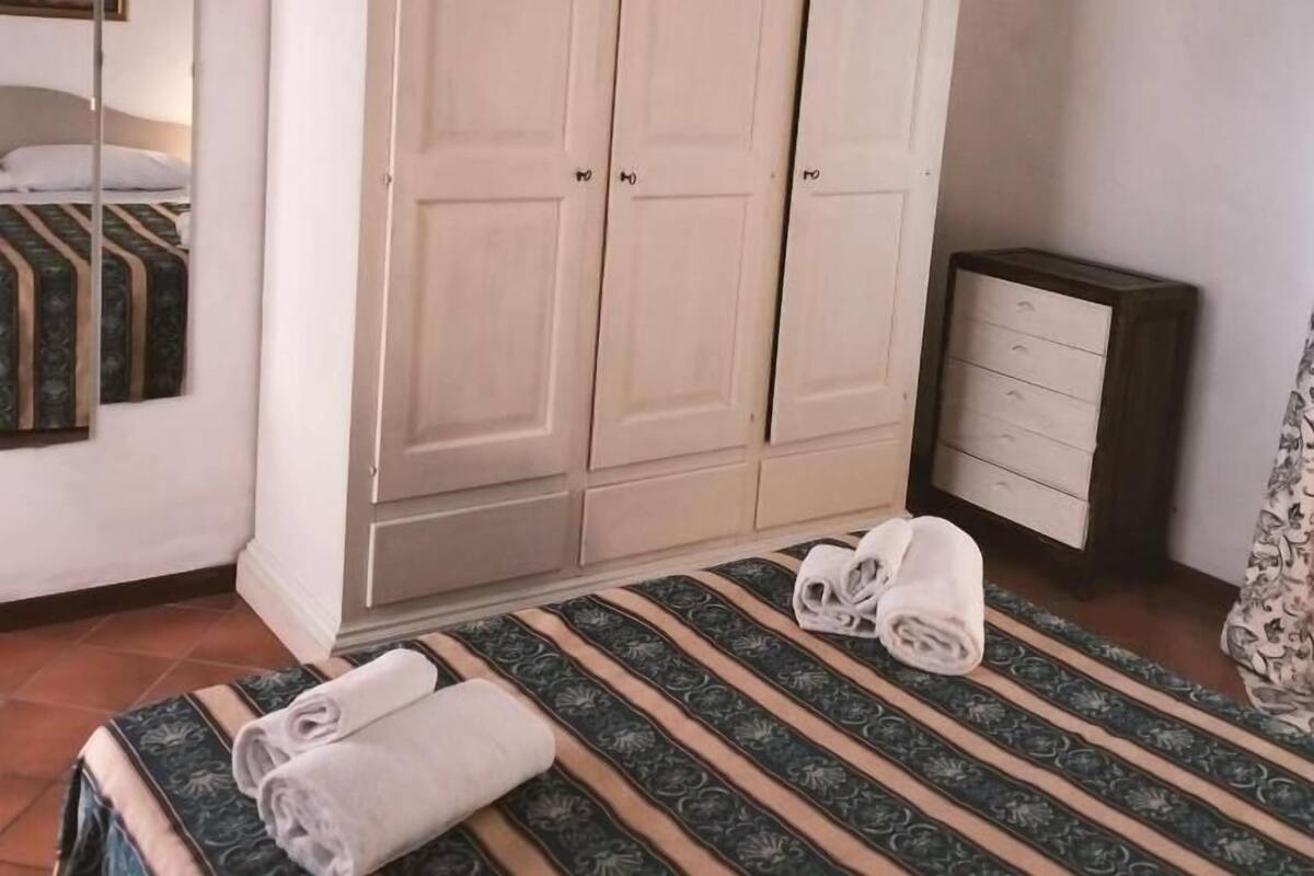 Quarto com cama, guarda-roupa, penteadeira e espelho.