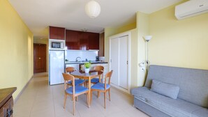 Um espaço compacto com cozinha americana, área de jantar com mesa e cadeiras, e um sofá cinza.