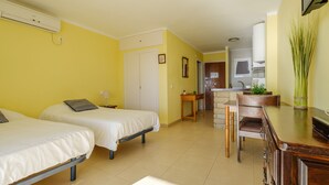 Quarto de hotel com duas camas, uma escrivaninha e uma cozinha compacta.