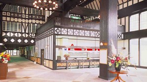 Um edifício em estilo japonês tradicional com fachada de madeira, janelas grandes e uma mesa de recepção.