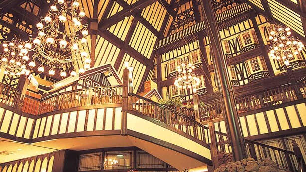 Um edifício com vários andares, vigas de madeira aparentes e uma sequência de varandas.