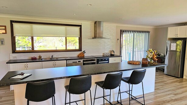 Cozinha moderna com uma ilha grande, banquetas e forno embutido.