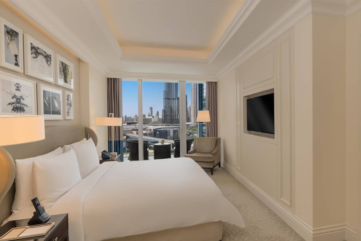 Quarto de hotel com uma cama grande, televisão, vista para a cidade e varanda.