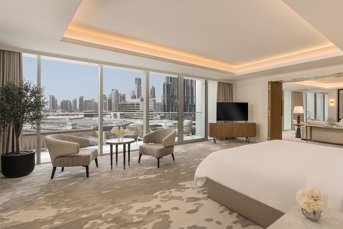Quarto de hotel moderno com uma cama grande, televisão, escrivaninha e varanda com vista para a cidade.