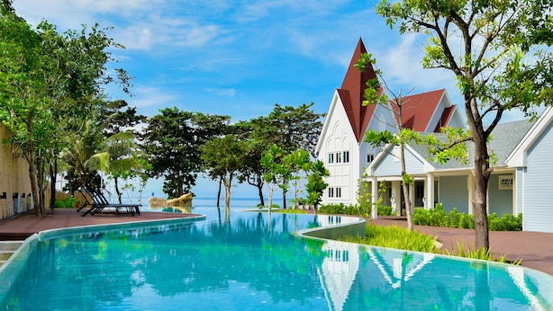 Um resort com piscina, um edifício semelhante a uma igreja e vegetação exuberante.