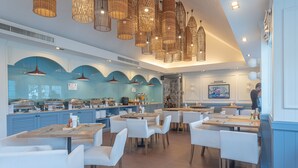 Um restaurante moderno com cadeiras e mesas brancas, um balcão com alimentos e luminárias de vime pendentes.