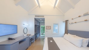 Quarto de hotel moderno com uma cama grande, uma escrivaninha com televisão de tela plana, um guarda-roupa e vista para o exterior.