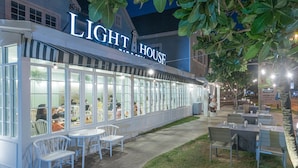 Um restaurante chamado "LIGHT HOUSE" com mesas ao ar livre e vista para a rua.