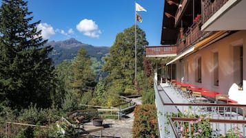 Restaurante com vista para a montanha, mesas ao ar livre e uma bandeira.
