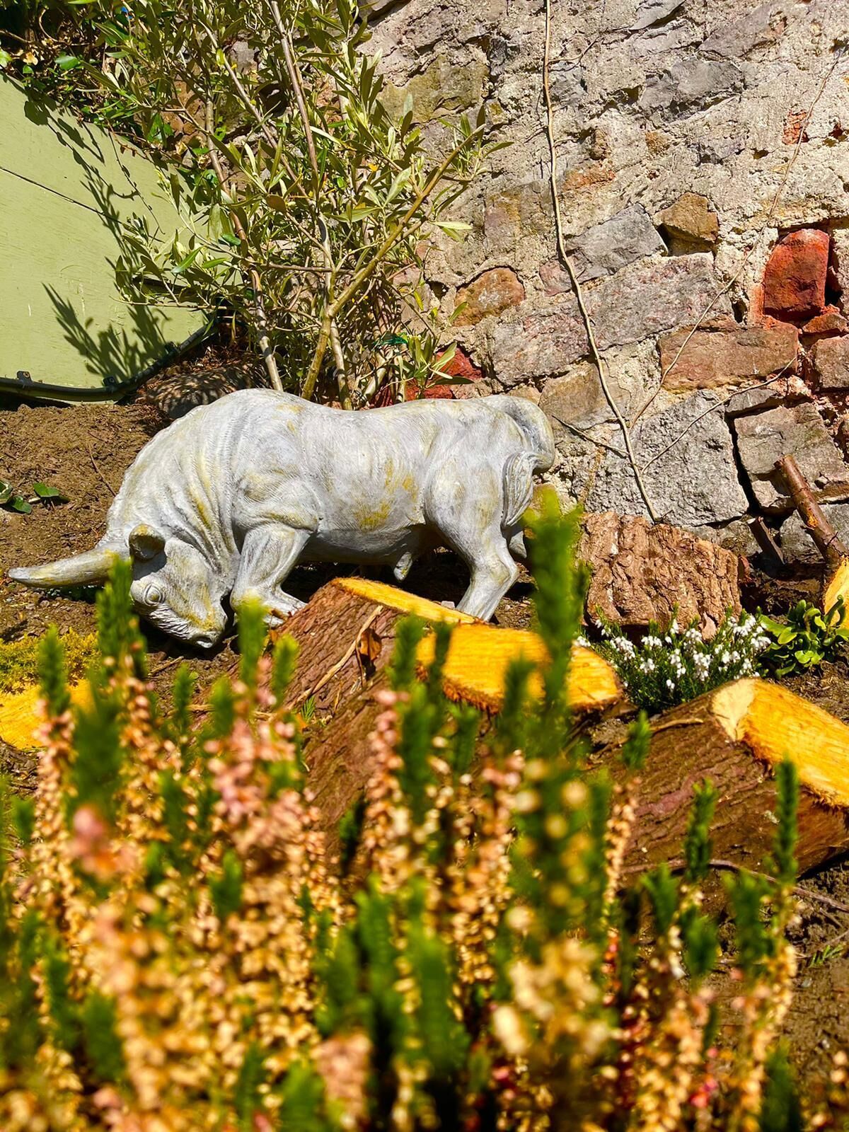 Mural de pedra com estátua de leão em um jardim.