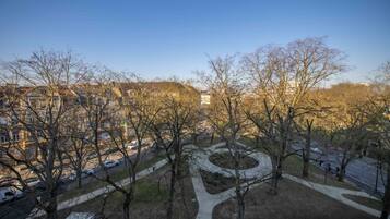 Um parque com caminhos, árvores e uma vista distante de edifícios.