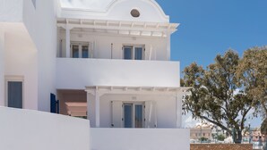 Um edifício branco com varanda, porta e janela com persianas.
