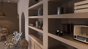 Um interior moderno com uma cadeira de madeira, prateleiras com objetos decorativos e um rádio antigo.
