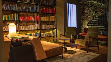 Um espaço aconchegante para leitura, com estante, assentos confortáveis e uma janela grande.
