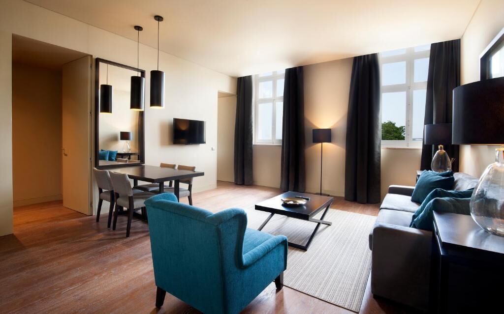 Uma sala de estar moderna com sofá, poltrona, mesa de jantar e televisão.