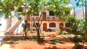 Um pátio com um edifício que apresenta uma escadaria, janelas em arco e uma rede.