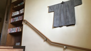 Uma escada de madeira com corrimão, uma estante repleta de livros e um tecido estampado na parede.