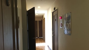 Um corredor com piso de madeira, uma porta à esquerda e um mural à direita.