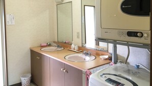 Casa de banho com duas pias, espelho e secador de cabelo.