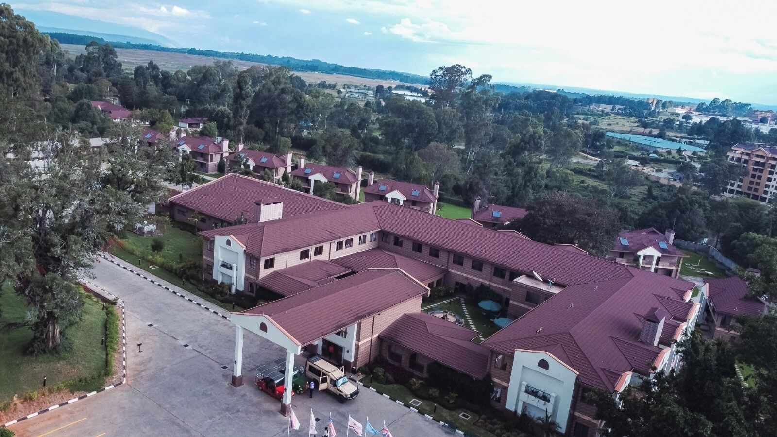 Um edifício grande, com vários andares e um pátio central, rodeado por árvores e campos abertos.
