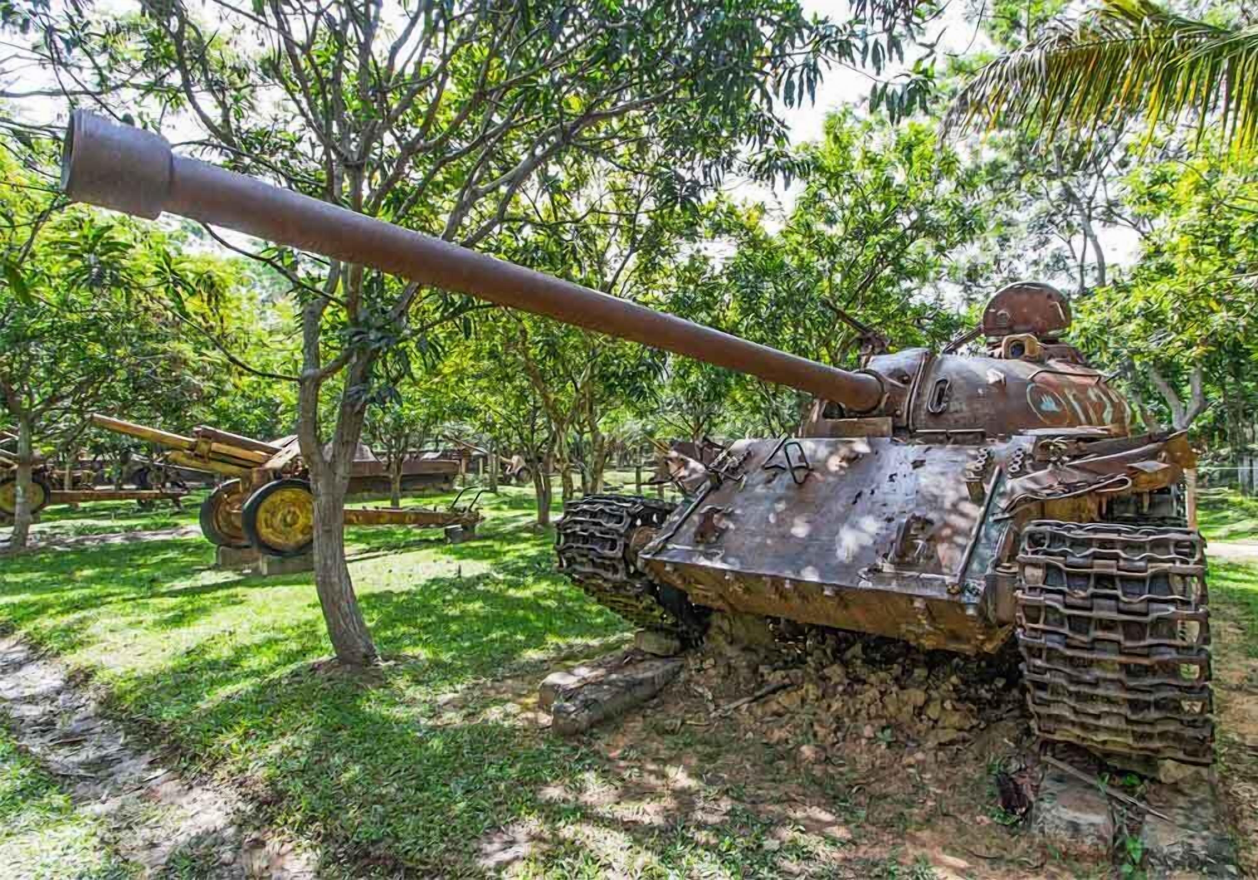 Um tanque militar em um parque com árvores e grama.