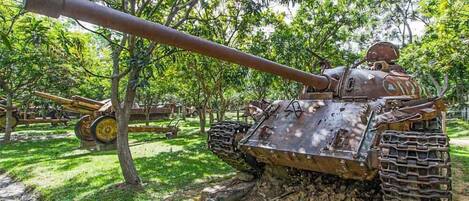 Um tanque militar em um parque com árvores e grama.