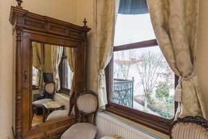 Quarto com um espelho grande, uma cadeira, um radiador e uma janela com cortinas.